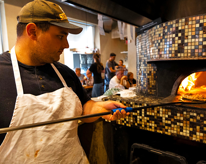 The pizza maestro at work, wielding his peel like a conductor's baton. Great pizza, like great music, requires both precision and passion.