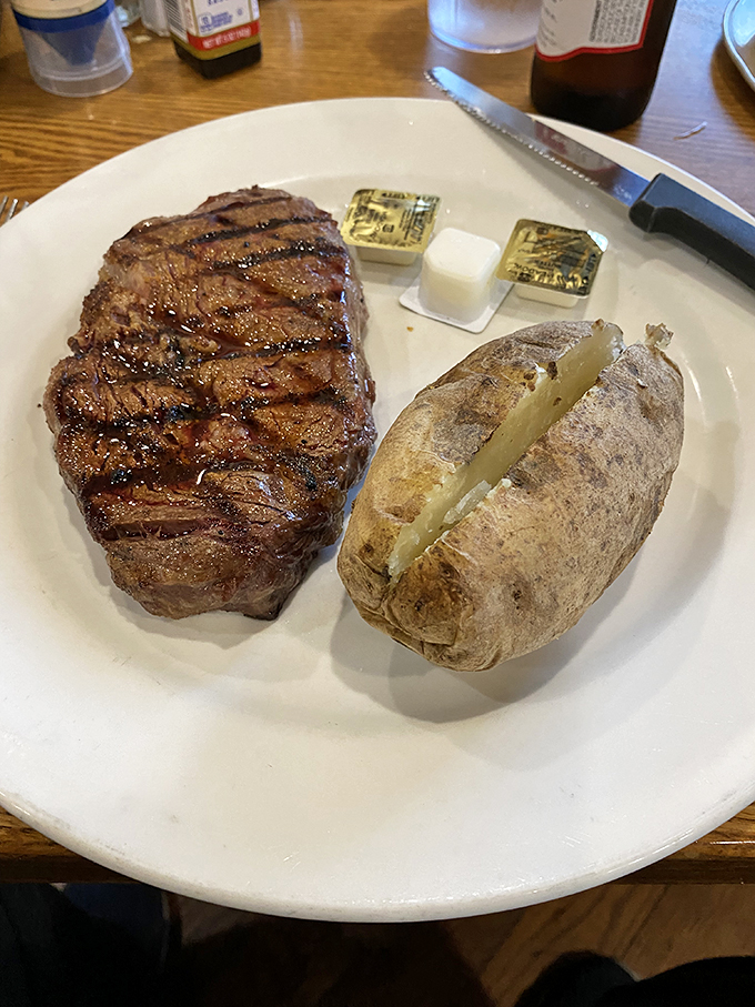 This beautifully seared steak with loaded baked potato represents American steakhouse tradition done absolutely right.
