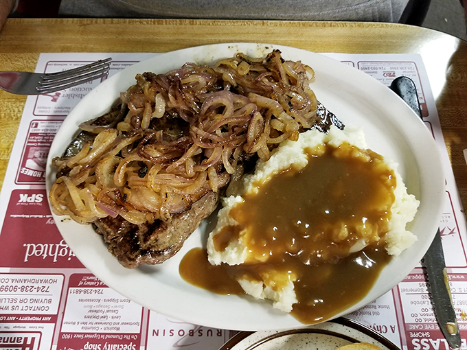 A steak topped with caramelized onions alongside mashed potatoes drowning in gravy. This plate doesn't just satisfy hunger &ndash; it creates happiness.