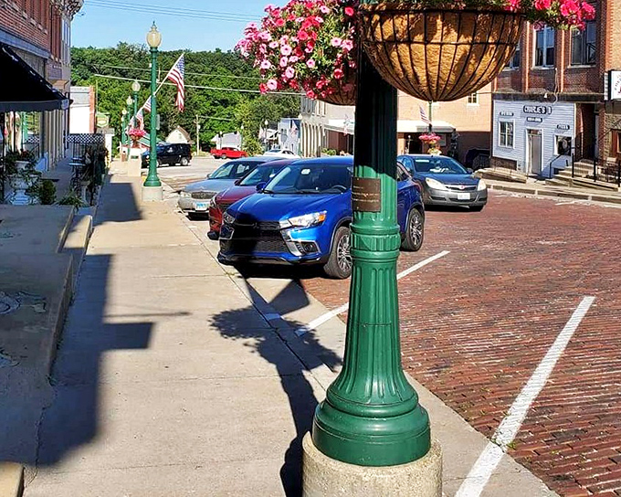Hanging baskets burst with petunias while green lampposts stand sentinel over streets that have witnessed generations of small-town life.