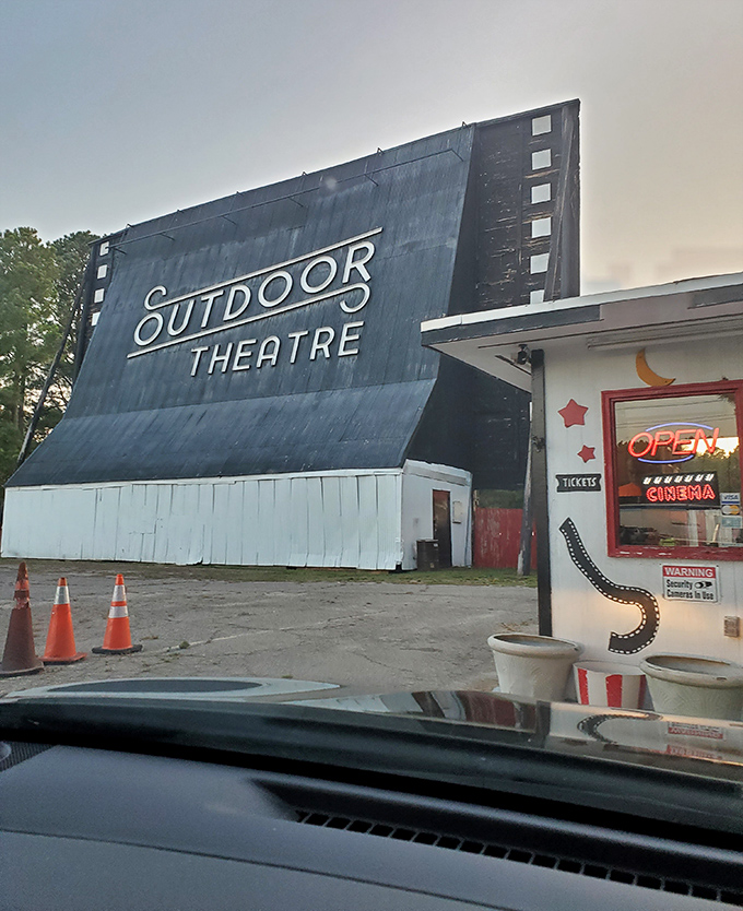 The "OPEN" sign glows with promise, a neon invitation to trade your living room for starlight cinema and communal joy.