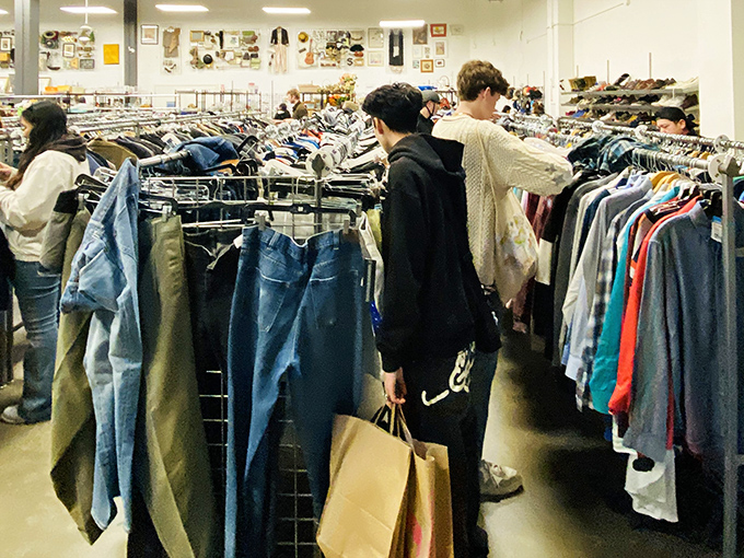 The universal posture of thrift shoppers: that slight forward lean, eyes scanning, fingers flicking through hangers with the focus of archaeologists on a dig.