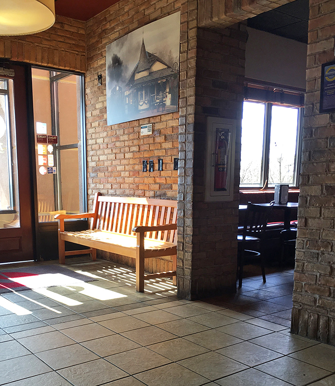 Sunlight streams through the entrance, creating a welcoming glow. The wooden bench invites you to pause briefly before your taste buds' adventure begins.