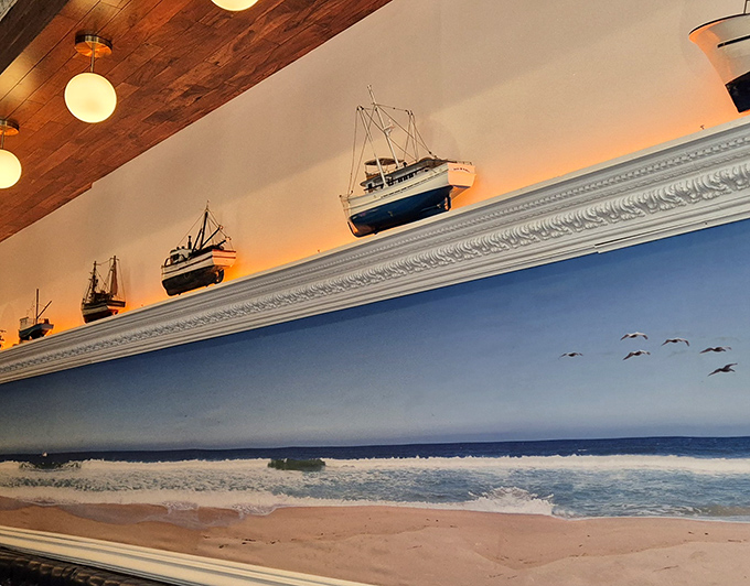 Maritime art and model ships sail above the dining room, creating an atmosphere that whispers "coastal getaway" rather than shouting "themed restaurant."