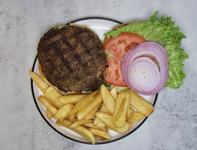 A burger that requires both hands and a strategy session. Perfectly charred patty, garden-fresh toppings, and fries that deserve their own fan club.