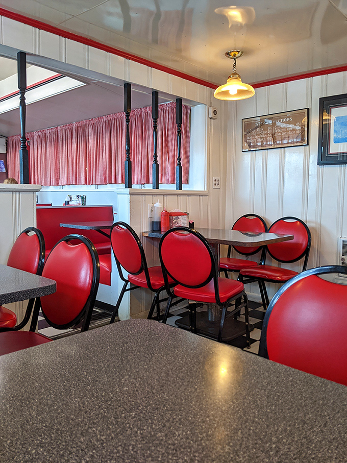 Red chairs stand at attention around laminate tables, ready for the next shift of hungry customers seeking refuge from their own cooking.
