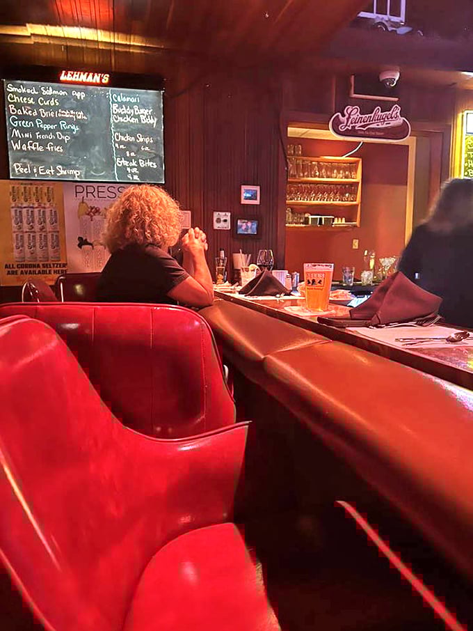 Red leather bar stools invite you to settle in for stories and sips. The chalkboard menu hints at treasures beyond the dining room.