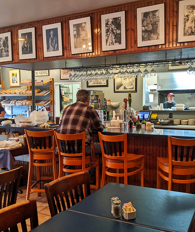 The bar area&mdash;where framed photographs tell stories and hanging wine glasses promise good decisions waiting to be made.