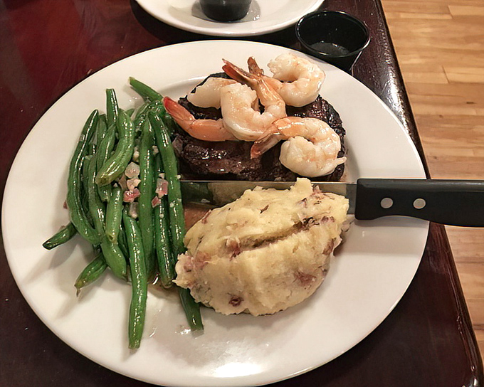 Surf meets turf in perfect harmony! Those plump shrimp perched atop a steak deserve their own thank-you note, while green beans add color and conscience.