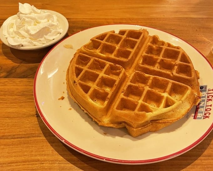 A perfect Belgian waffle sits proudly on its plate, golden squares creating little pools for maple syrup to gather like tiny lakes of sweetness.