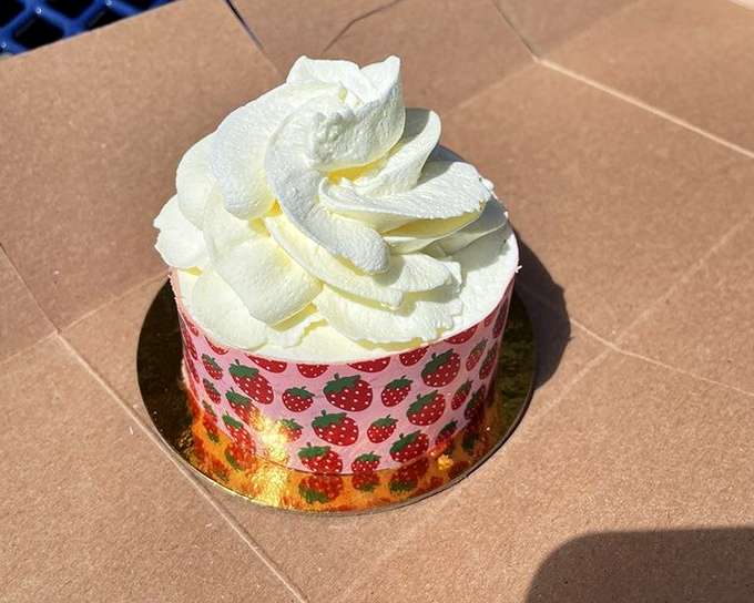 A strawberry-patterned cake topped with a cloud of whipped cream. It's like summer decided to throw itself a birthday party.