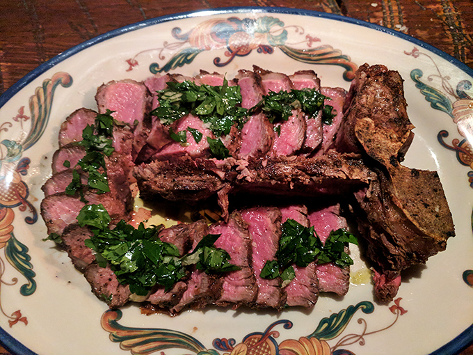 Bistecca sliced to reveal a perfect medium-rare interior. This isn't just steak&mdash;it's a carnivore's dream dressed in herbs and good intentions.