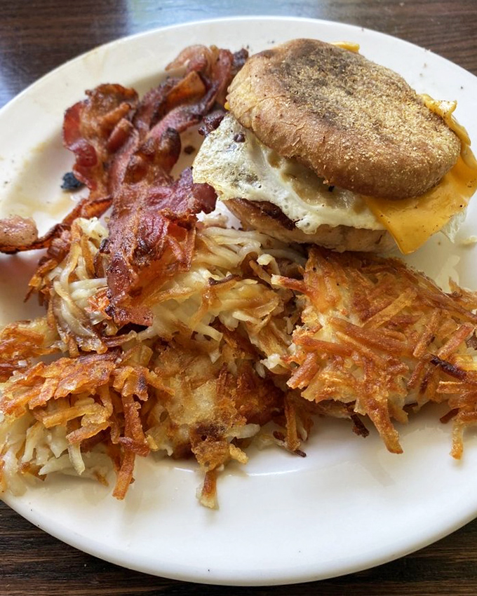 The breakfast sandwich trinity: golden English muffin, melty cheese, and farm-fresh eggs with crispy bacon and hash browns as loyal sidekicks.