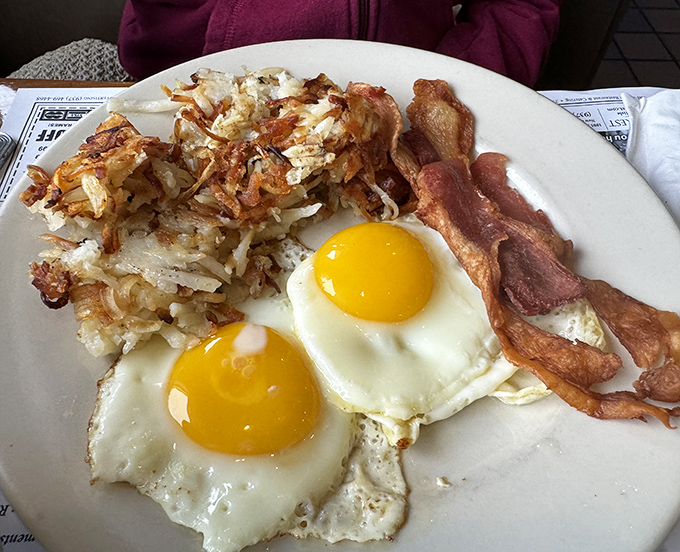 Breakfast of champions: sunny-side up eggs, crispy hash browns, and bacon cooked to perfection. Morning glory on a plate.