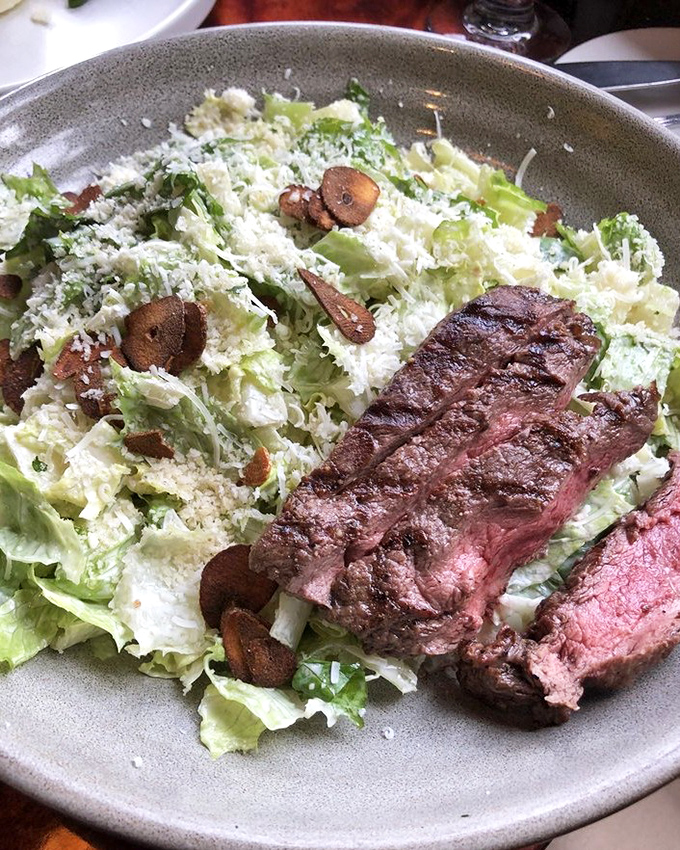 Caesar salad crowned with perfectly grilled steak transforms a simple side into a magnificent main course.