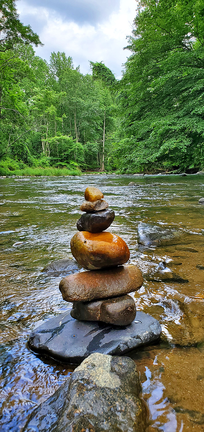 Nature creates its own balancing act beneath the bridge, with carefully stacked stones marking moments of zen in rushing waters.