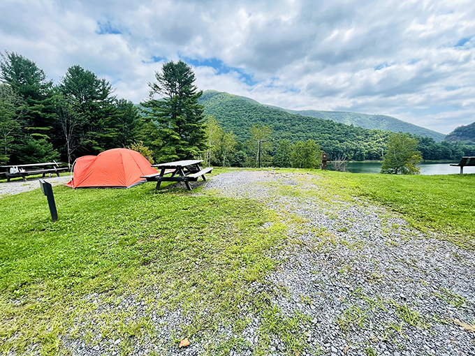 Camping with a view that beats any five-star hotel balcony. That orange tent pops against the landscape like nature's exclamation point. 