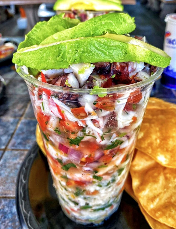 This ceviche isn't just mixed; it's curated – a glass of citrus-kissed seafood topped with avocado slices like emerald crowns.