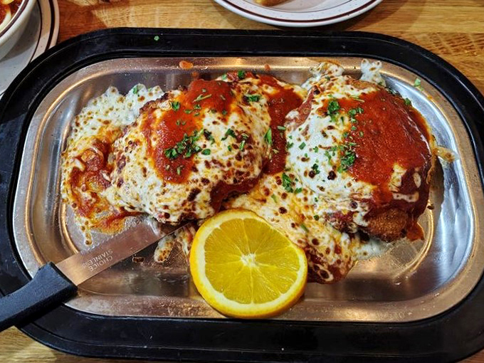 Chicken Parmesan sizzling in its own little skillet theater, where melted cheese and marinara sauce perform their timeless Italian romance.