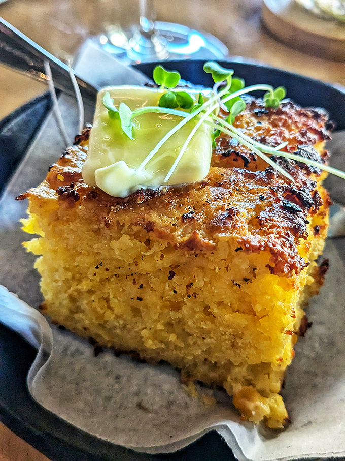 This cornbread square topped with herb butter isn't just a side&mdash;it's a revelation. Golden, crusty edges give way to a tender interior.