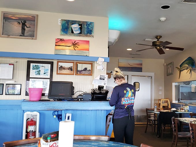 Behind the counter, where island magic happens. Those beach paintings aren't just decoration&mdash;they're a promise of the experience to come.