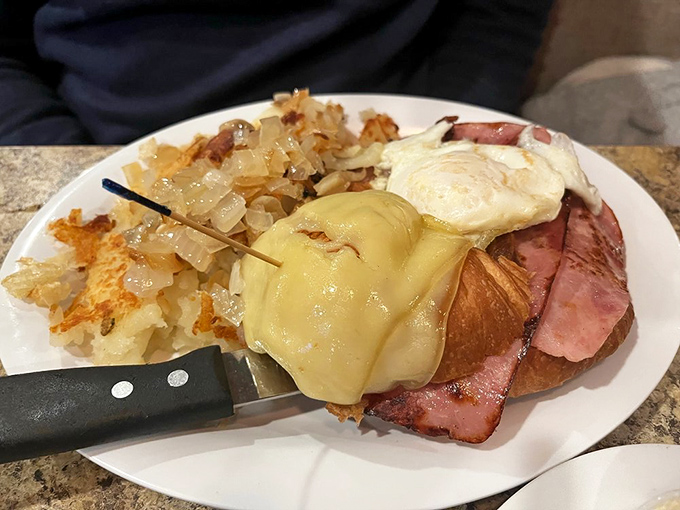 Breakfast architecture at its finest &ndash; layers of ham, egg, and cheese on a croissant with home fries standing guard nearby.