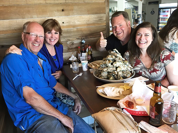 The universal expression of seafood happiness&mdash;diners gathered around a mountain of shellfish, proving that the best meals are measured in empty shells and satisfied smiles.