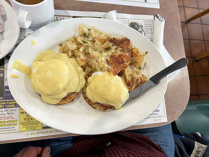 Eggs Benedict with hollandaise sauce so yellow it could moonlight as a traffic signal, paired with home fries that demand to be devoured.