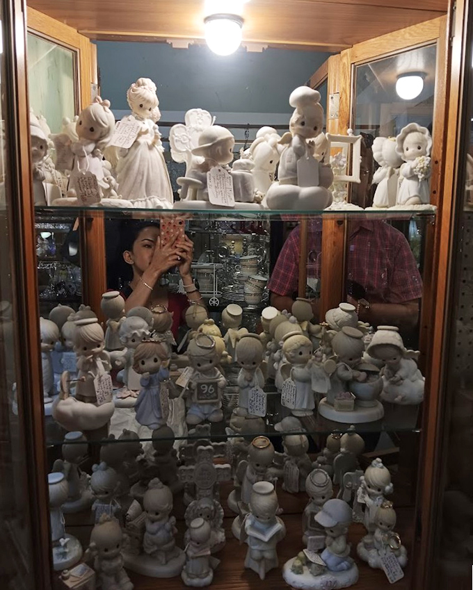 An army of Precious Moments figurines stands guard in their glass fortress. Their innocent eyes have seen decades come and go.