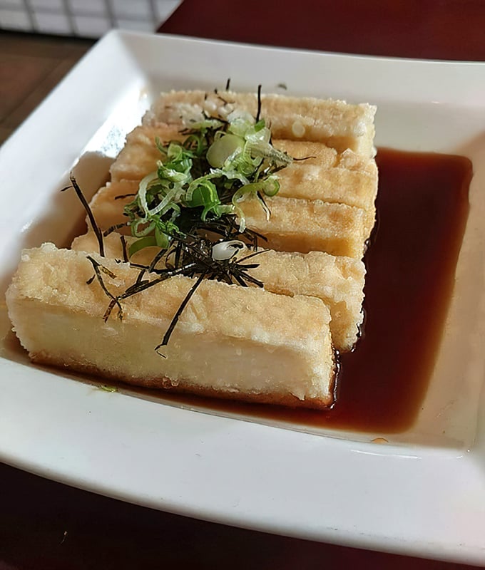 Agedashi tofu floating in a savory broth &ndash; proof that bean curd can be transformed into something worth fighting over.