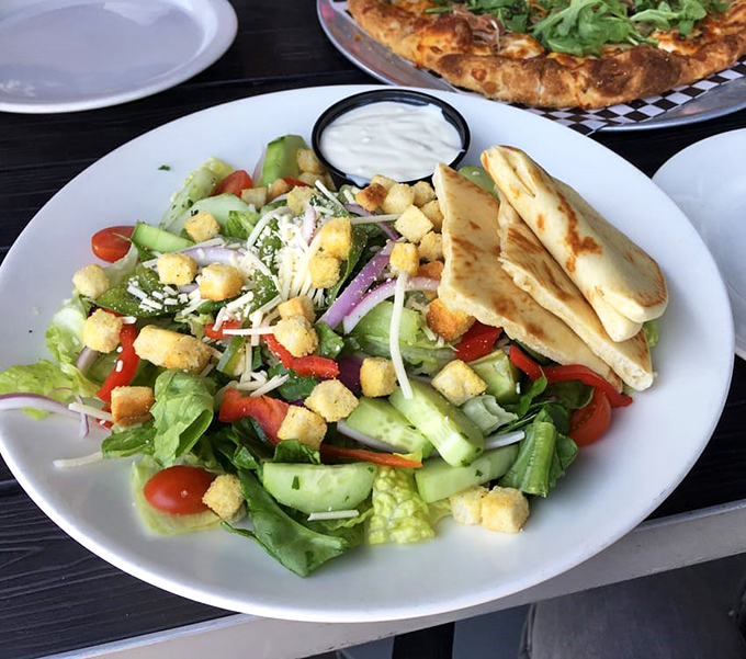 A garden salad that doesn't feel like punishment, with fresh vegetables, croutons, and pita bread that proves healthy options can still bring joy.
