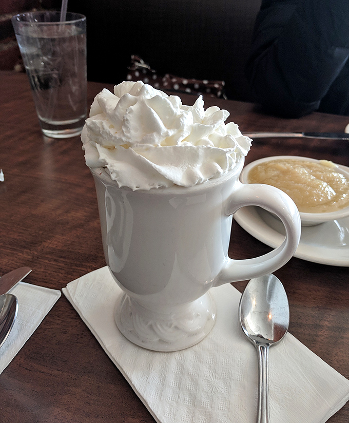 This isn't just hot chocolate; it's a warm hug in a mug, crowned with a cloud of whipped cream that defies both gravity and restraint.