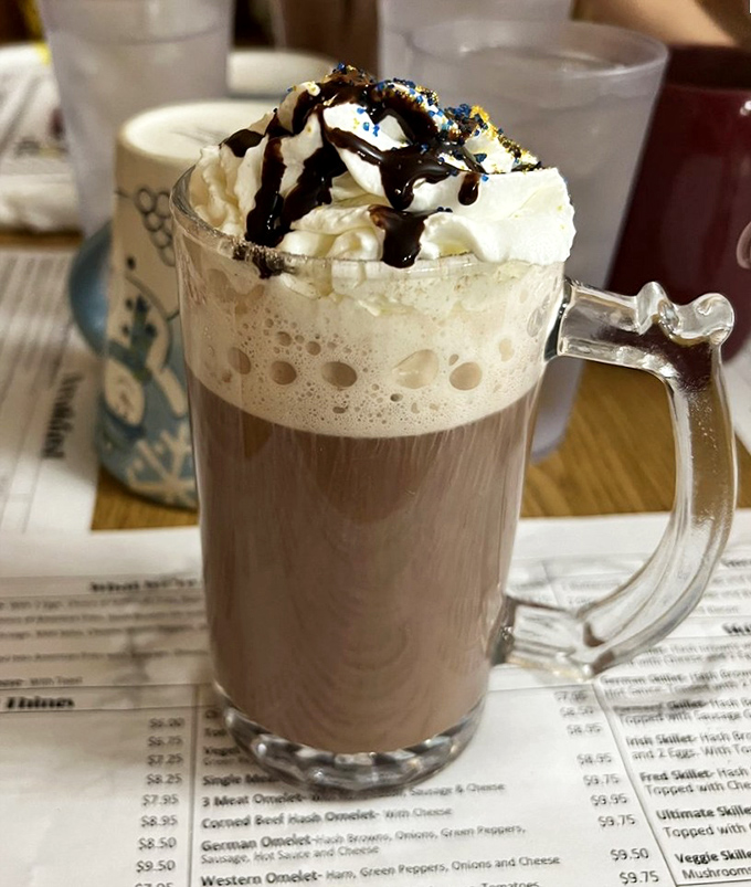 Hot chocolate that understands its assignment: whipped cream mountain, chocolate drizzle, and that glass mug that makes everything taste better. Winter blues, consider yourself defeated.