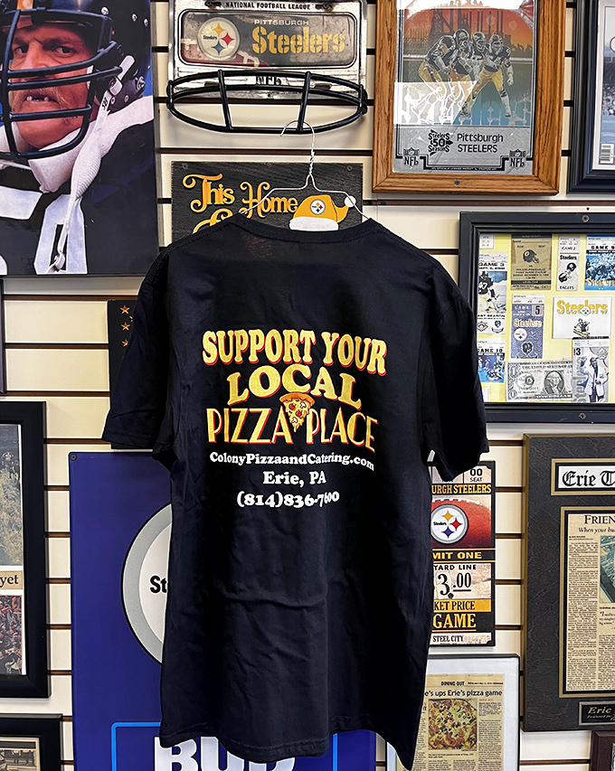 "Support Your Local Pizza Place"—a t-shirt that's less merchandise and more community manifesto hanging among sports memories.