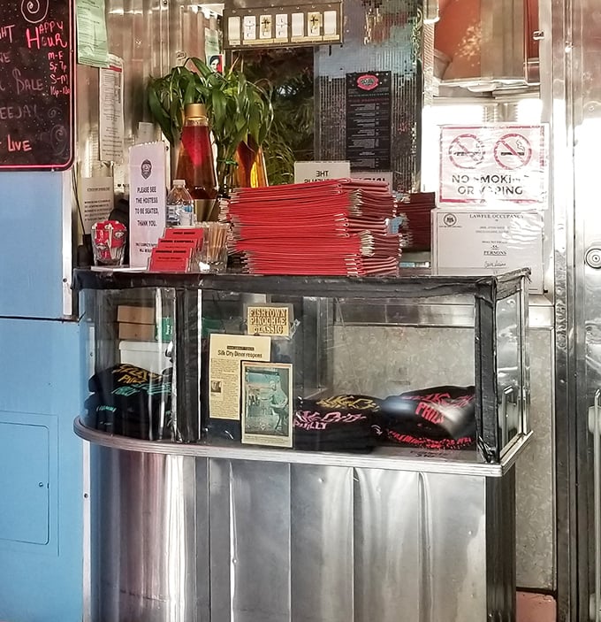 The host stand doubles as a merch counter because the only thing better than eating at Silk City is taking a piece of it home with you.