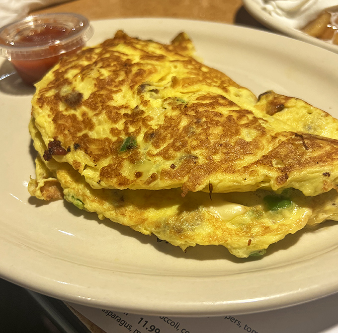 An omelet so perfectly folded it could teach origami classes. The golden exterior hides treasures within like a breakfast pirate chest.