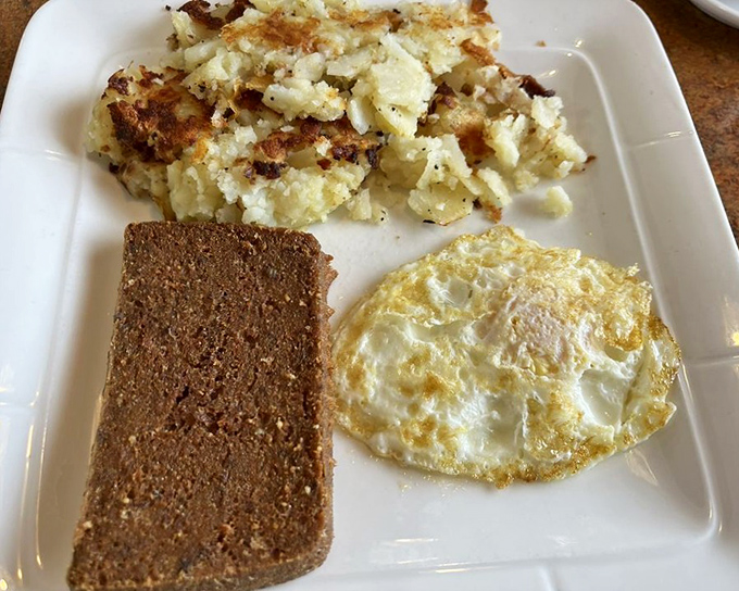 The breakfast trinity: crispy home fries, a slice of hearty bread, and a sunny-side-up egg that's just waiting to release its golden treasure.