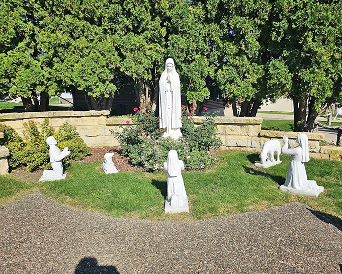 A serene garden shrine where white statues create a moment of contemplation amid the more exuberant decorative elements nearby.