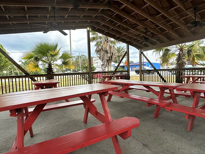 Florida's weather demands outdoor seating, and these red picnic tables under a shaded pavilion deliver the perfect casual dining atmosphere for seafood enjoyment.