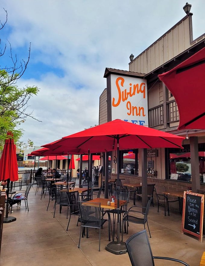 Red umbrellas dot the patio like poppies in a field, creating an outdoor dining space that captures Temecula's perfect weather.