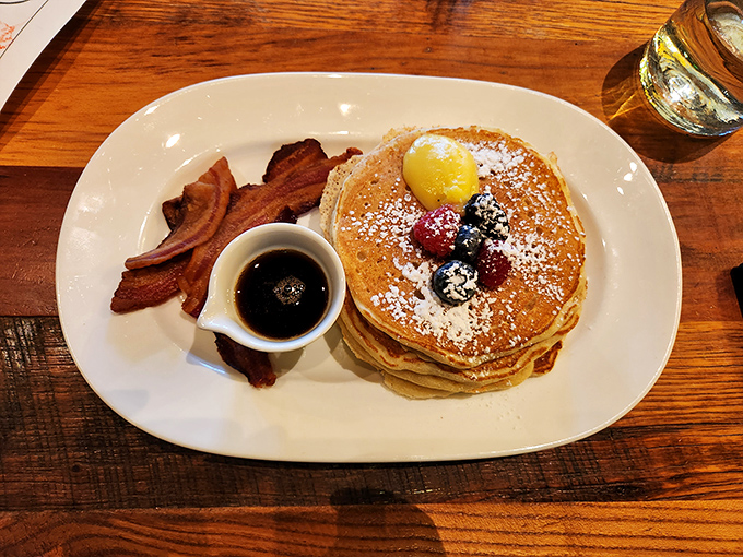 Pancakes stacked higher than my morning ambitions, dusted with powdered sugar and accompanied by bacon that's achieved perfect crispness. 