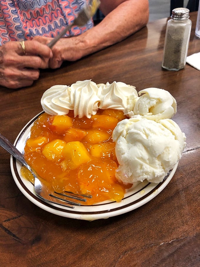 Peach cobbler that's having an identity crisis as a sundae&mdash;warm fruit, cool ice cream, and a dollop of whipped cream for good measure.