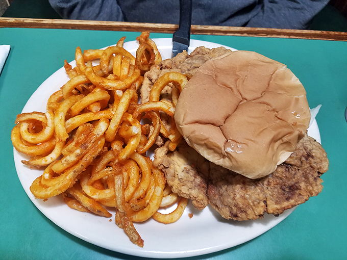 A pork tenderloin sandwich that's having an identity crisis&mdash;it thinks it's bigger than its bun. Those curly fries are practically doing gymnastics.