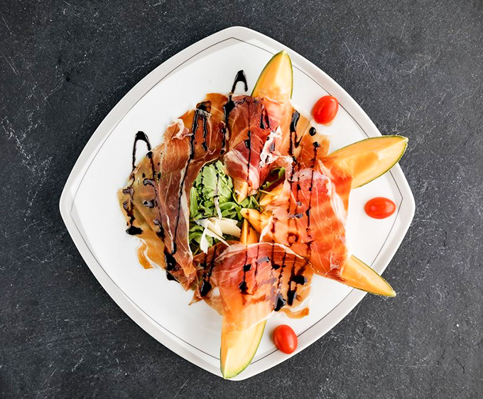 Prosciutto e melone&mdash;Italy's perfect answer to the sweet-and-salty debate, arranged like edible art on a plate.