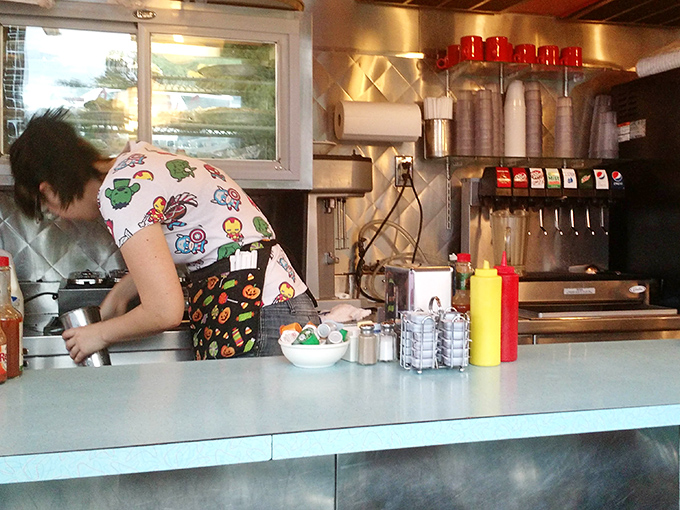 Condiments standing at attention, ready for duty. That colorful apron suggests serious breakfast business is underway. 