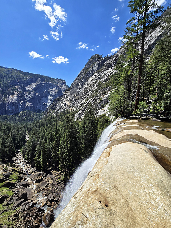 Standing at the edge where peaceful river transforms into thundering spectacle - nature's ultimate magic trick revealed.