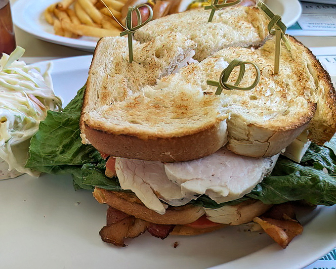 This club sandwich stands taller than most architectural achievements, secured with fancy toothpicks that make you feel like you've been invited to a party.