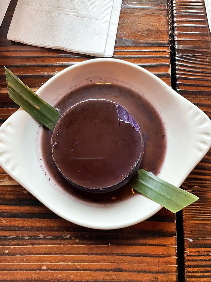 This isn't just dessert, it's a cultural handshake&mdash;ube flan that bridges continents with its silky purple perfection and banana leaf garnish.