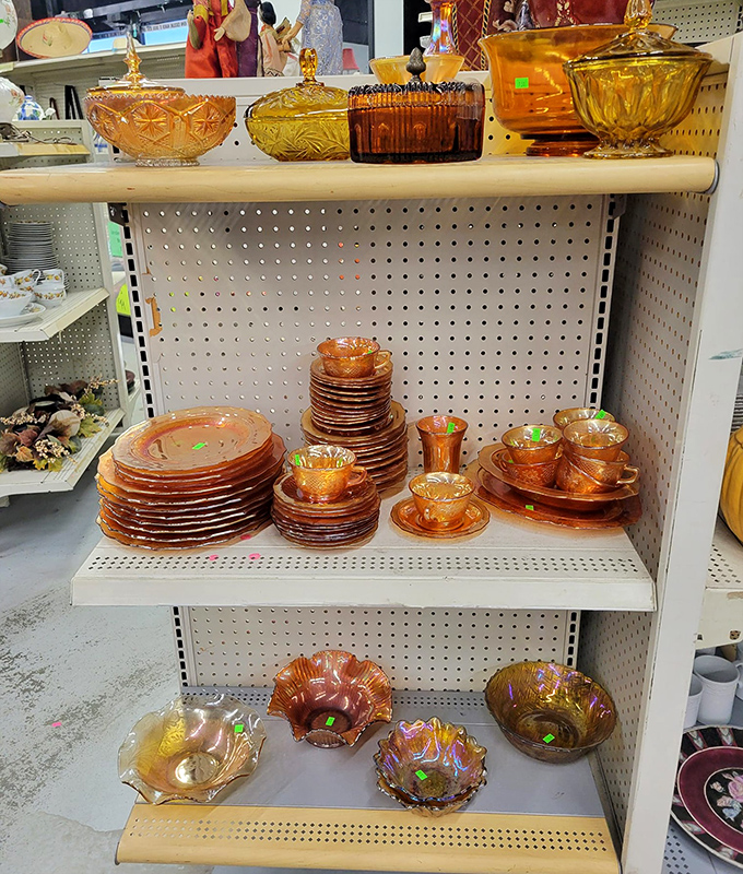 Amber carnival glass gleams like liquid sunshine on the shelf&mdash;each piece whispering stories of elegant dinner parties from decades past.