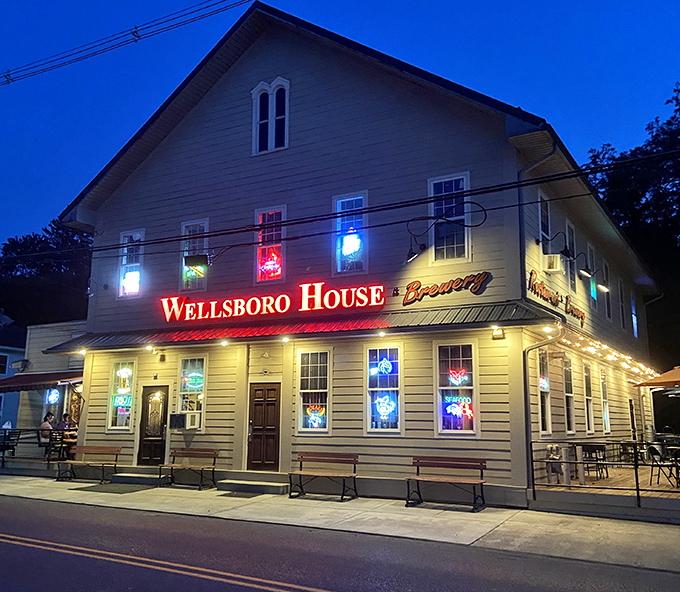 The Wellsboro House lights up the night with neon warmth, beckoning visitors with promises of craft brews and local conversation.